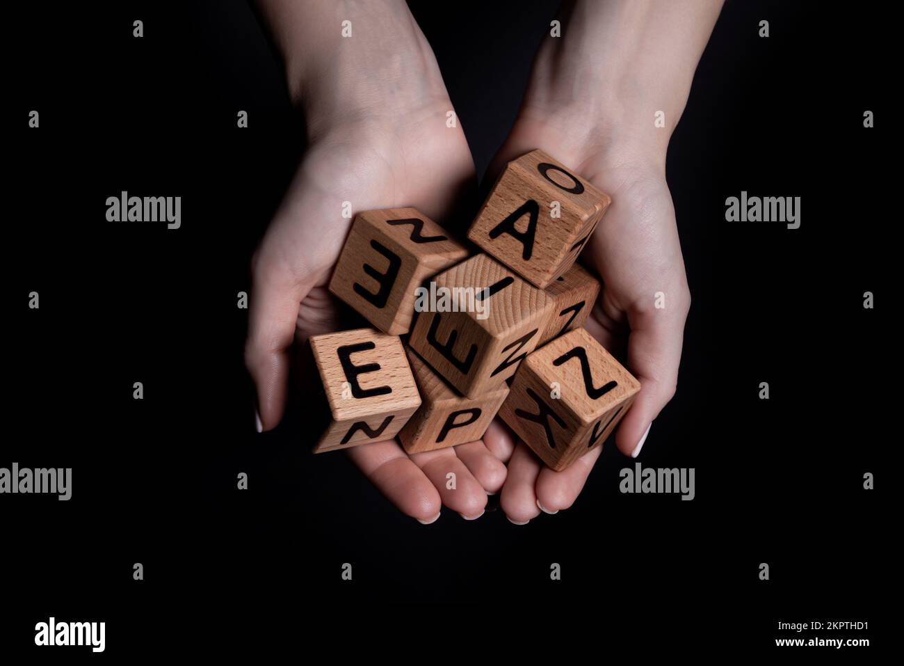 Female hands holds a cube with letters isolated on black background ...