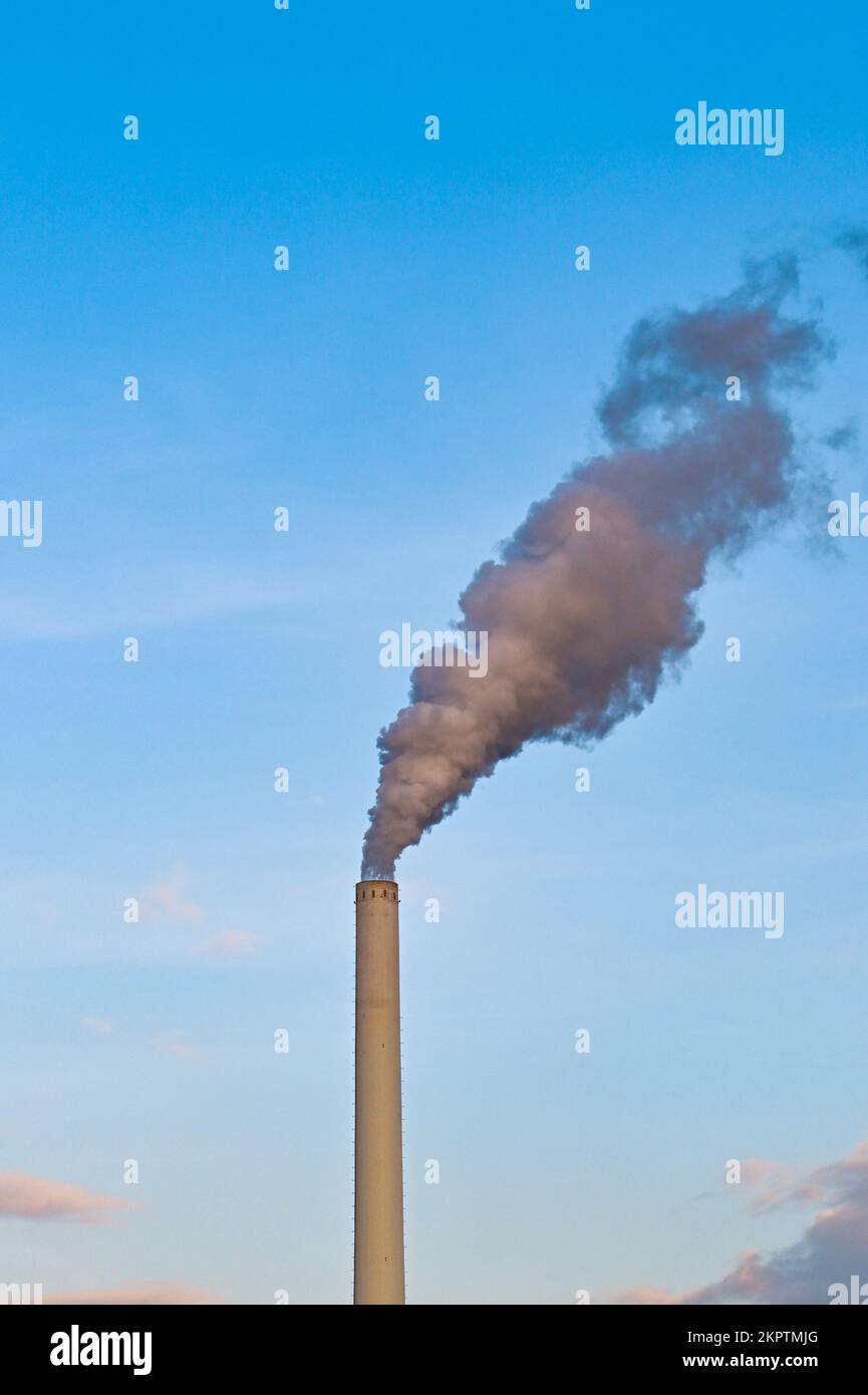 Smoke belching out of a tall chimney stack at a power station. No ...
