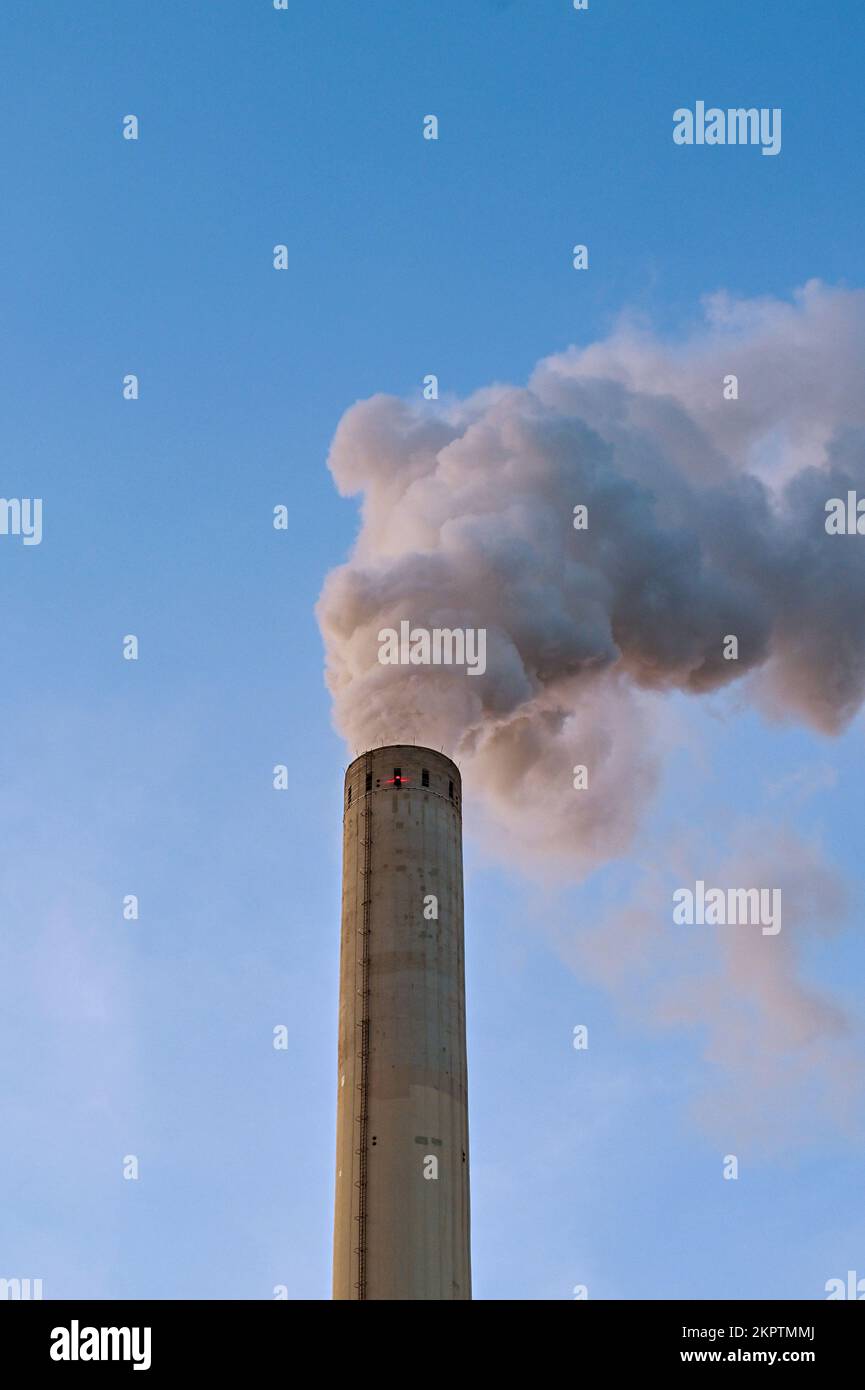Smoke belching out of a tall chimney stack at a power station. No ...