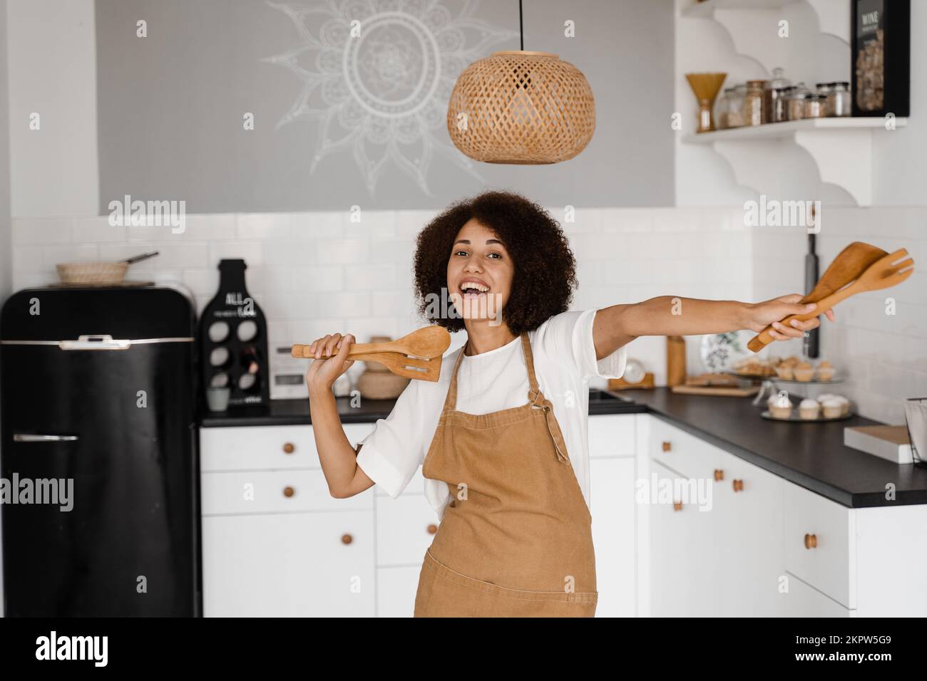 African girl cook in apron dancing on white kitchen. Advertising for ...