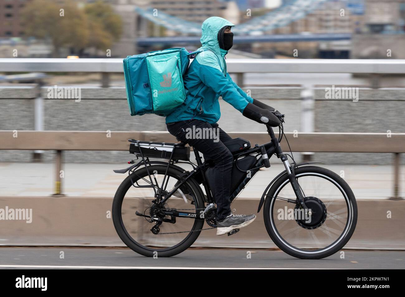 A deliveroo cycle courier riding an e-bike across, London Bridge, London, UK. 18 Nov 2022 Stock ...