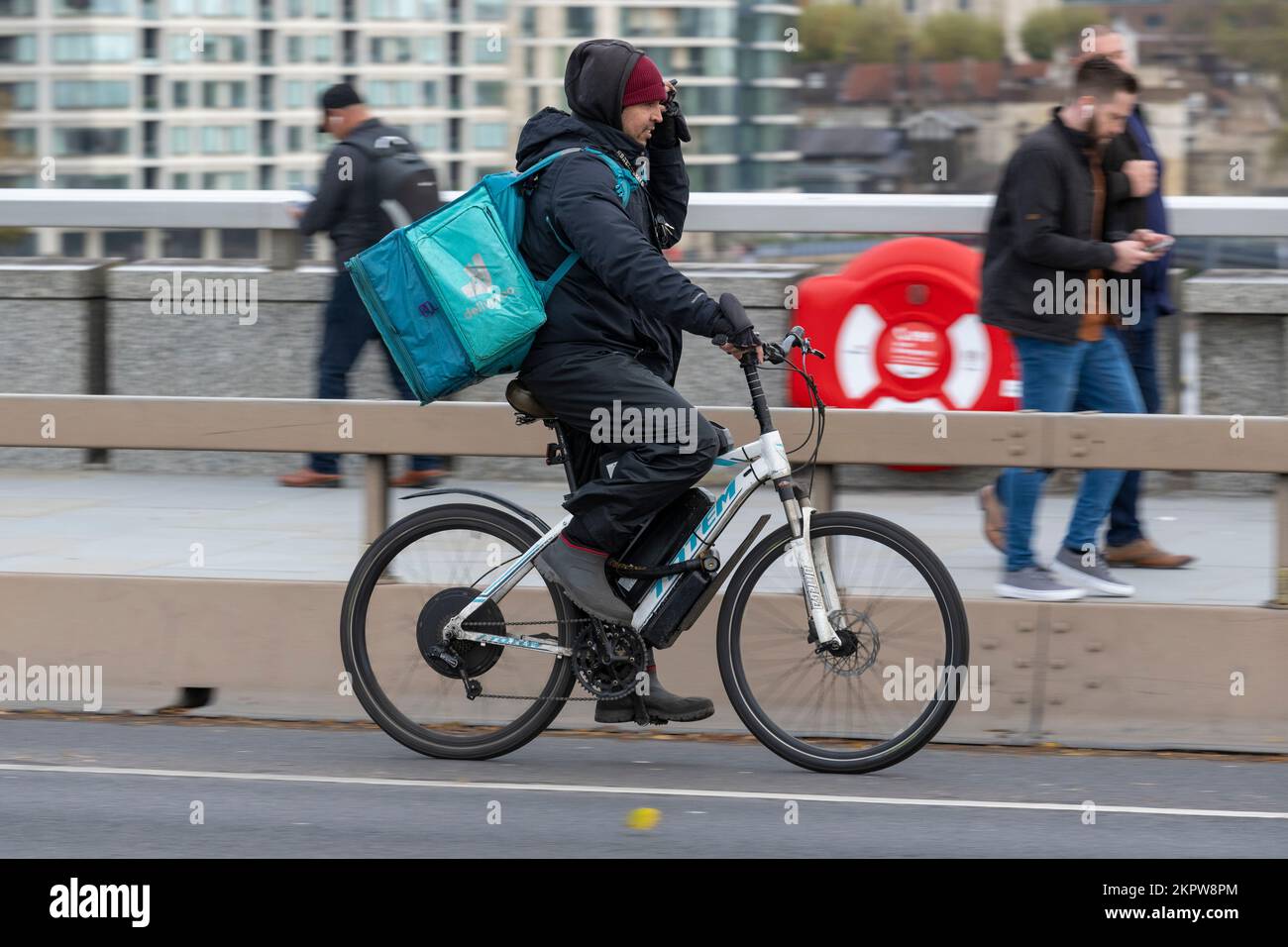 A deliveroo cycle courier riding an e-bike across, London Bridge, London, UK. 17 Nov 2022 Stock ...