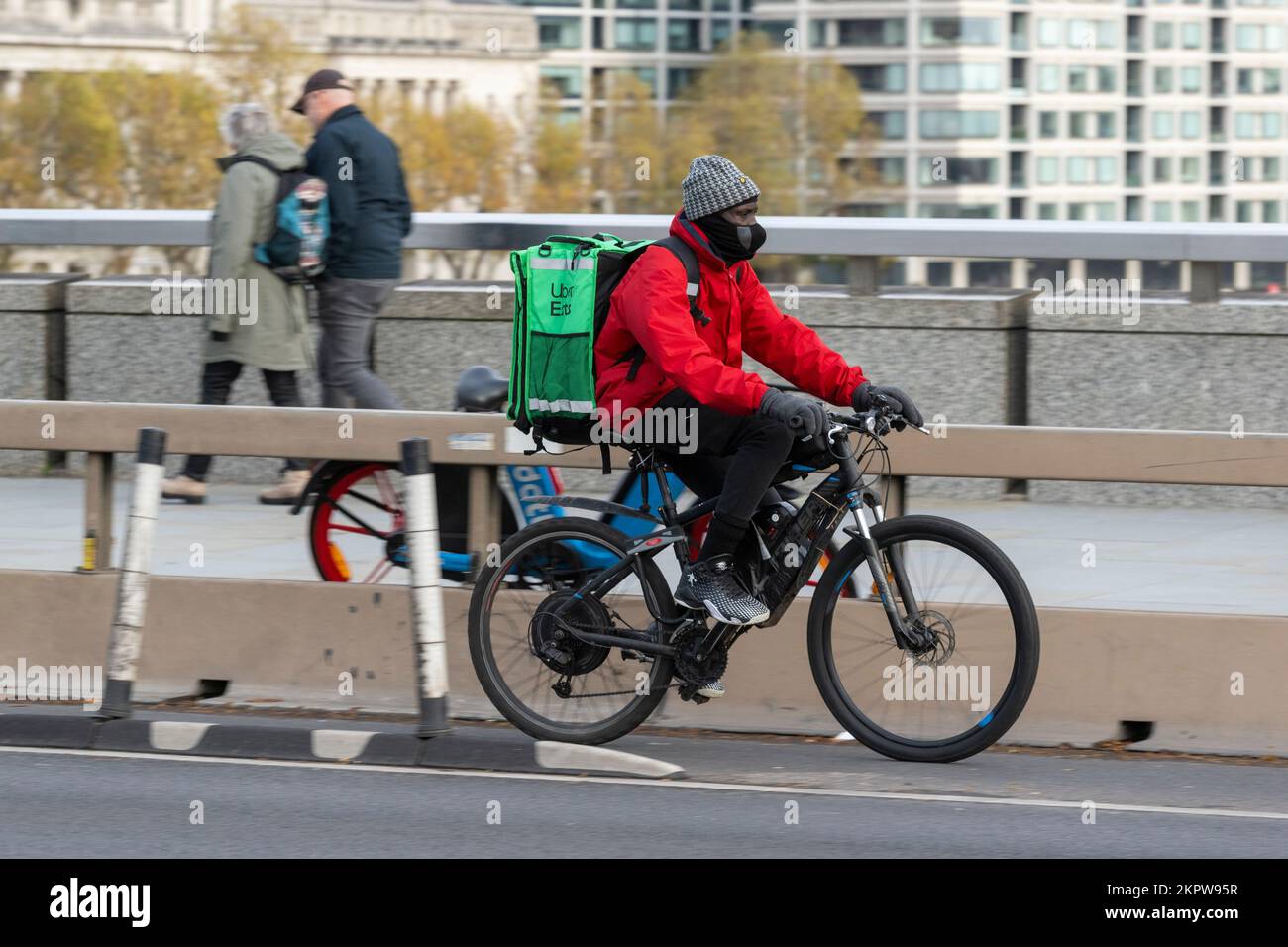 A Uber Eats cycle courier riding an e-bike across, London Bridge, London, UK. 17 Nov 2022 Stock ...