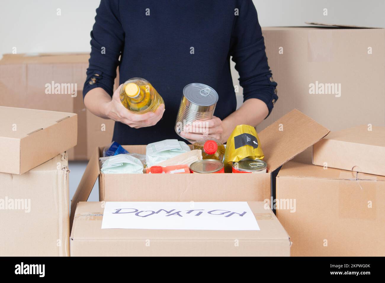Volunteer woman collecting food into donations box. Cardbox full of ...