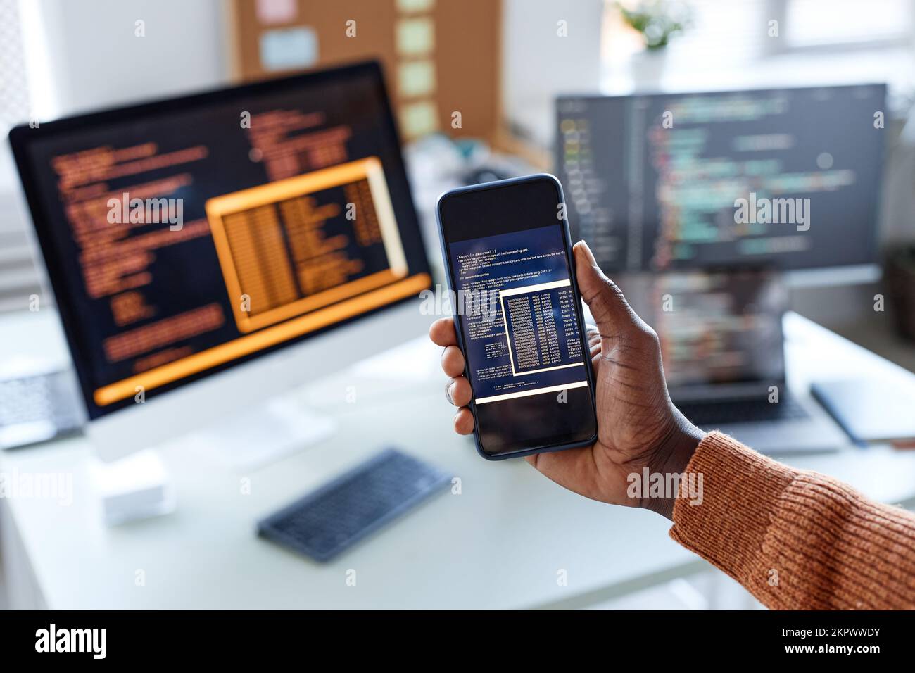 Hand of developer showing smartphone with code of new app on screen ...