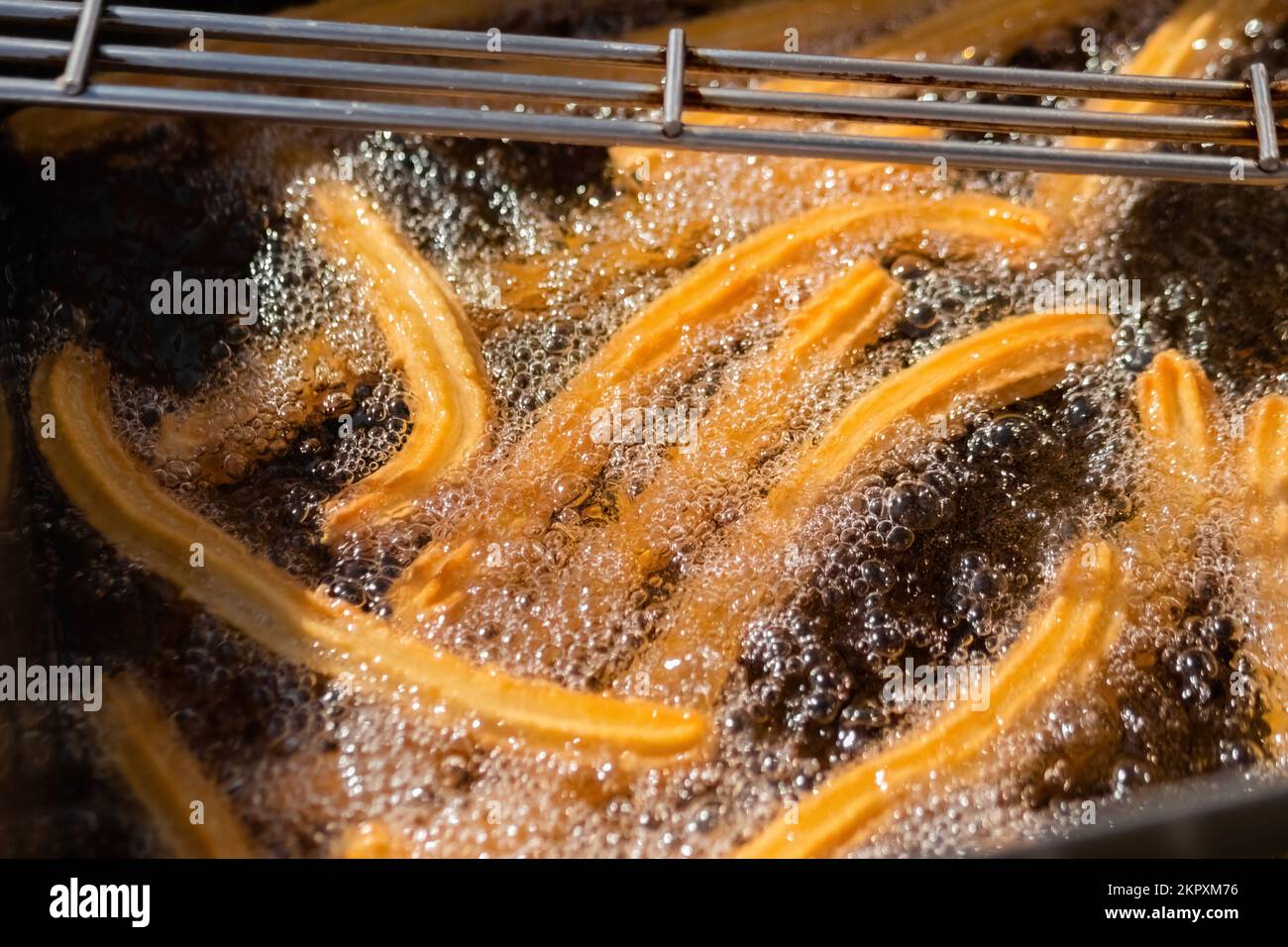 Process of cooking churros in boiling oil at street food market: close ...
