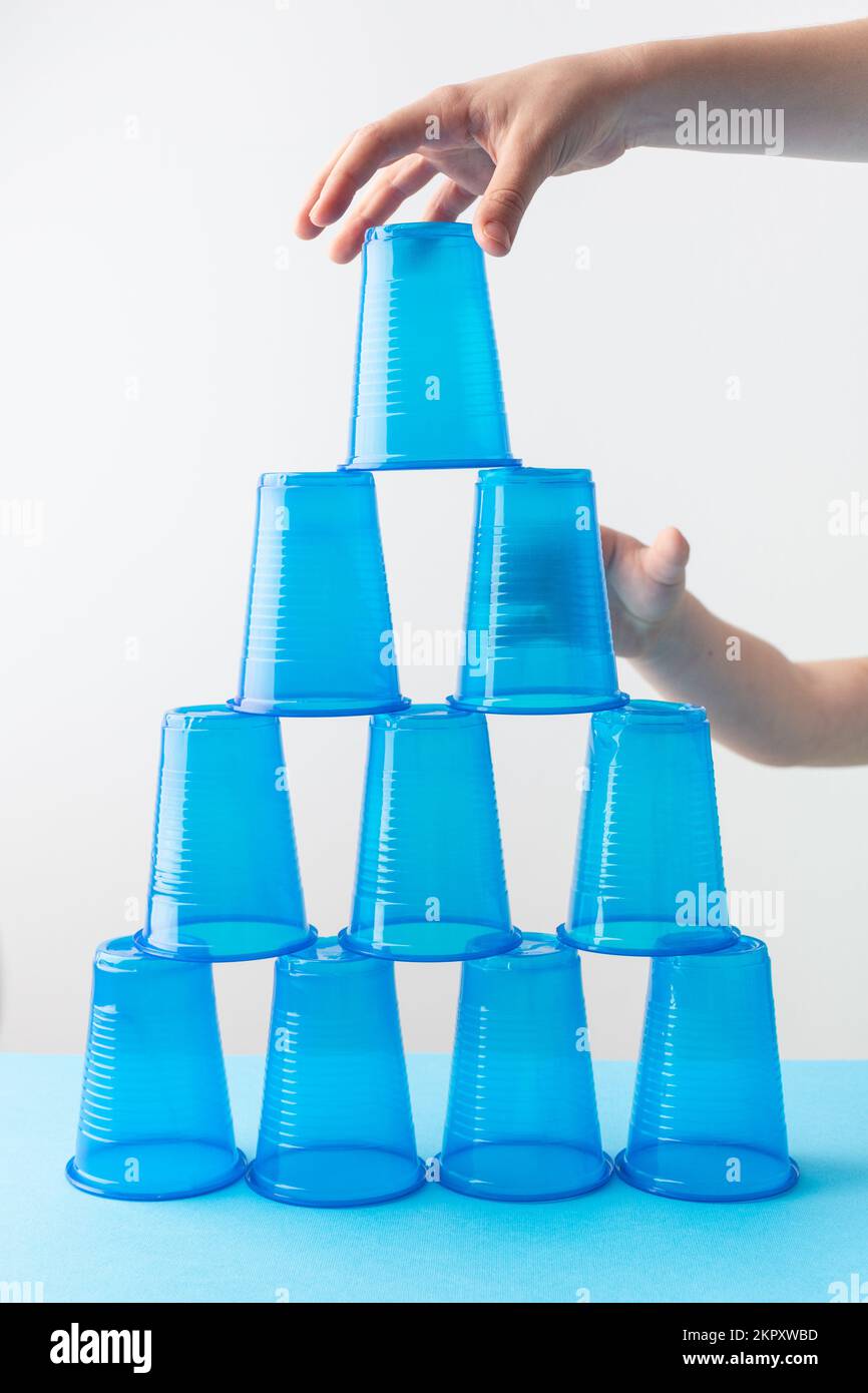 Pyramid of blue plastic cups. Set for party. Children hands Stock Photo ...