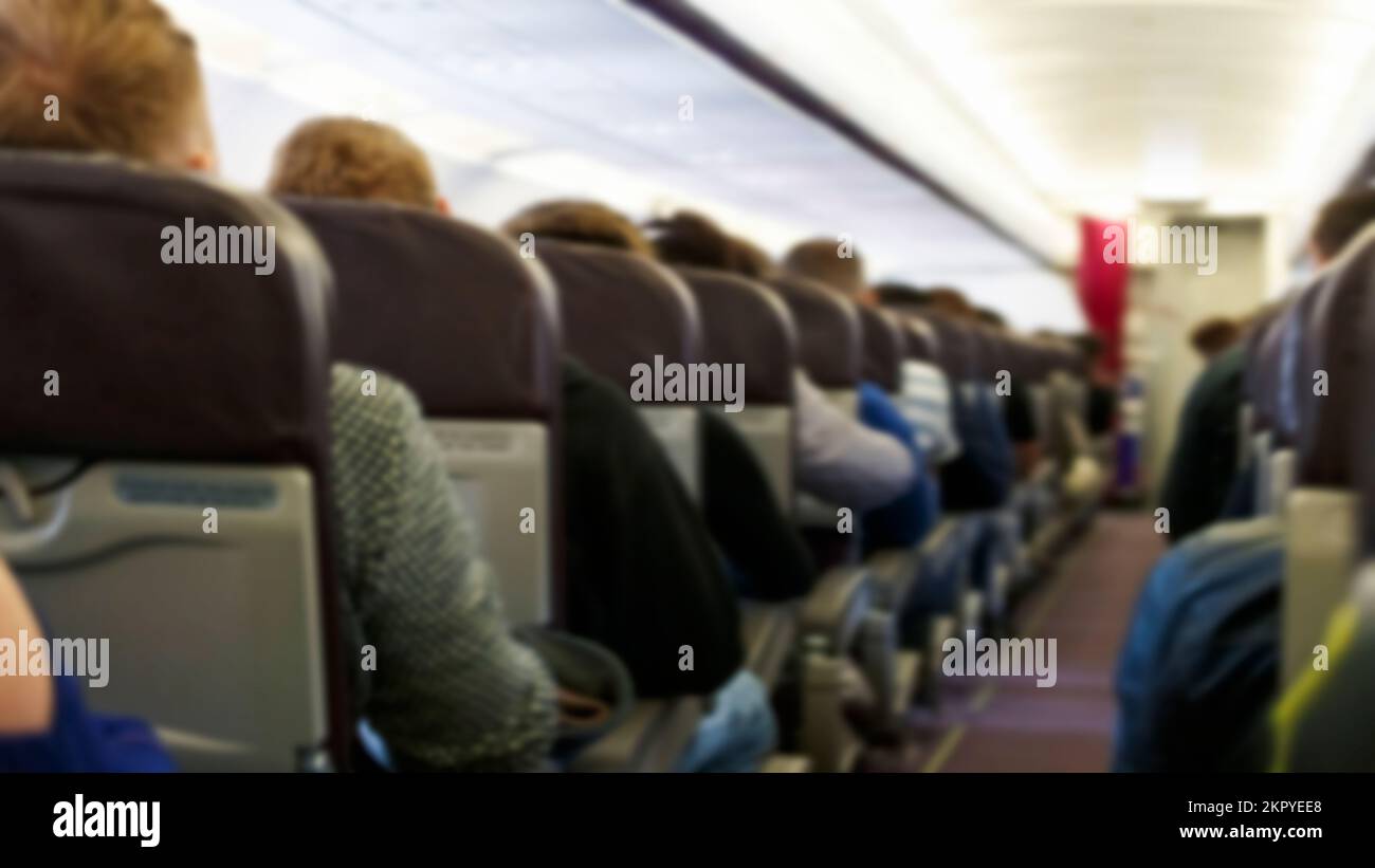 Blur background of passenger plane cabin with people sitting in ...