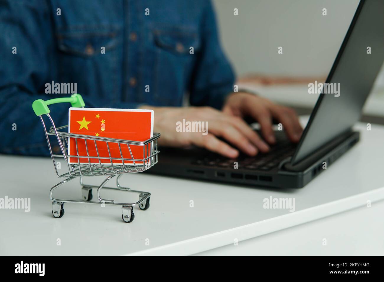 Small shopping cart with chinese flag on the table. Man using laptop ...