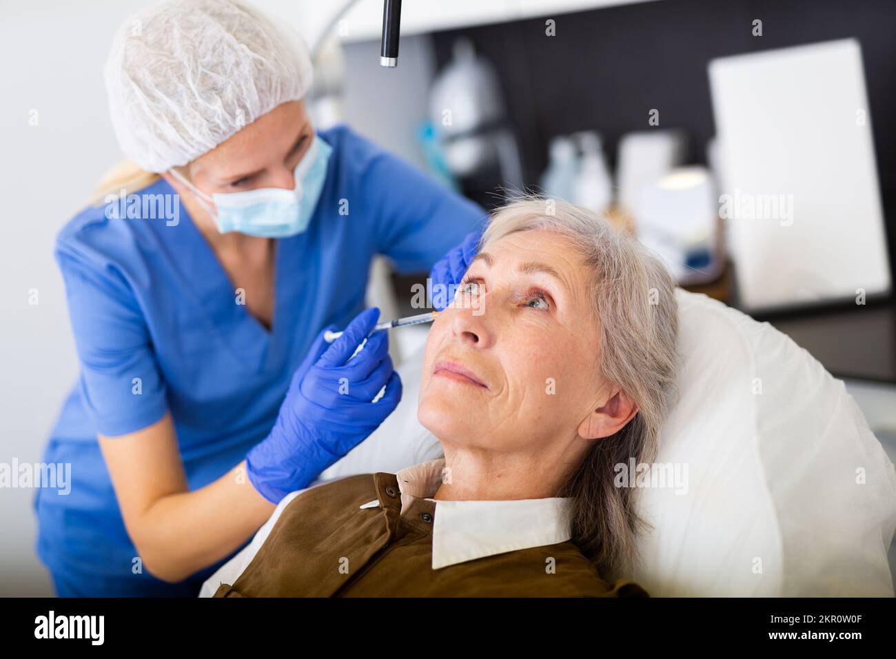 Elderly wman receiving procedure of face mesotherapy at cosmetology ...
