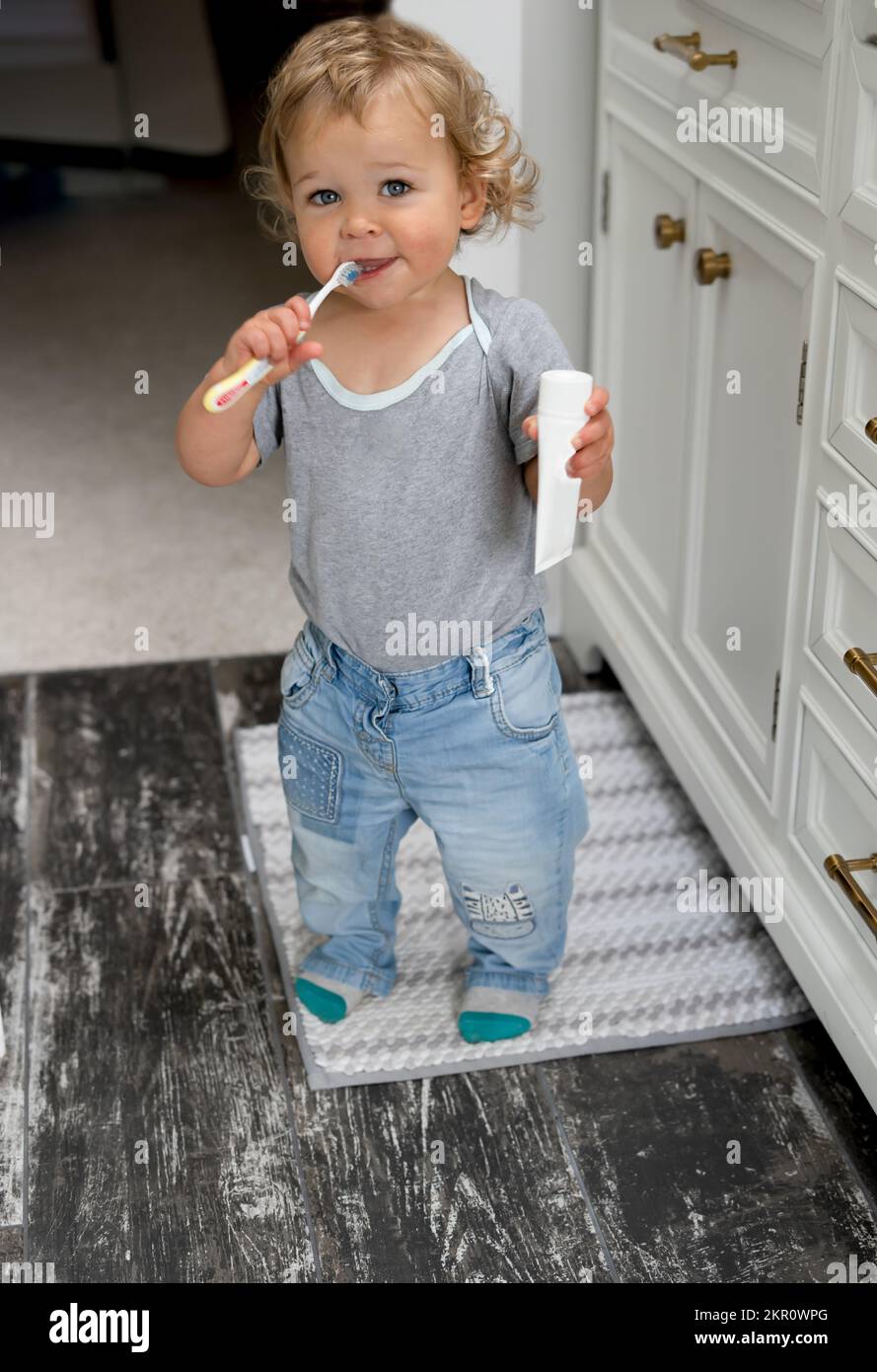 Portrait of a blonde boy with a toothpaste is cleaning teeth at home ...