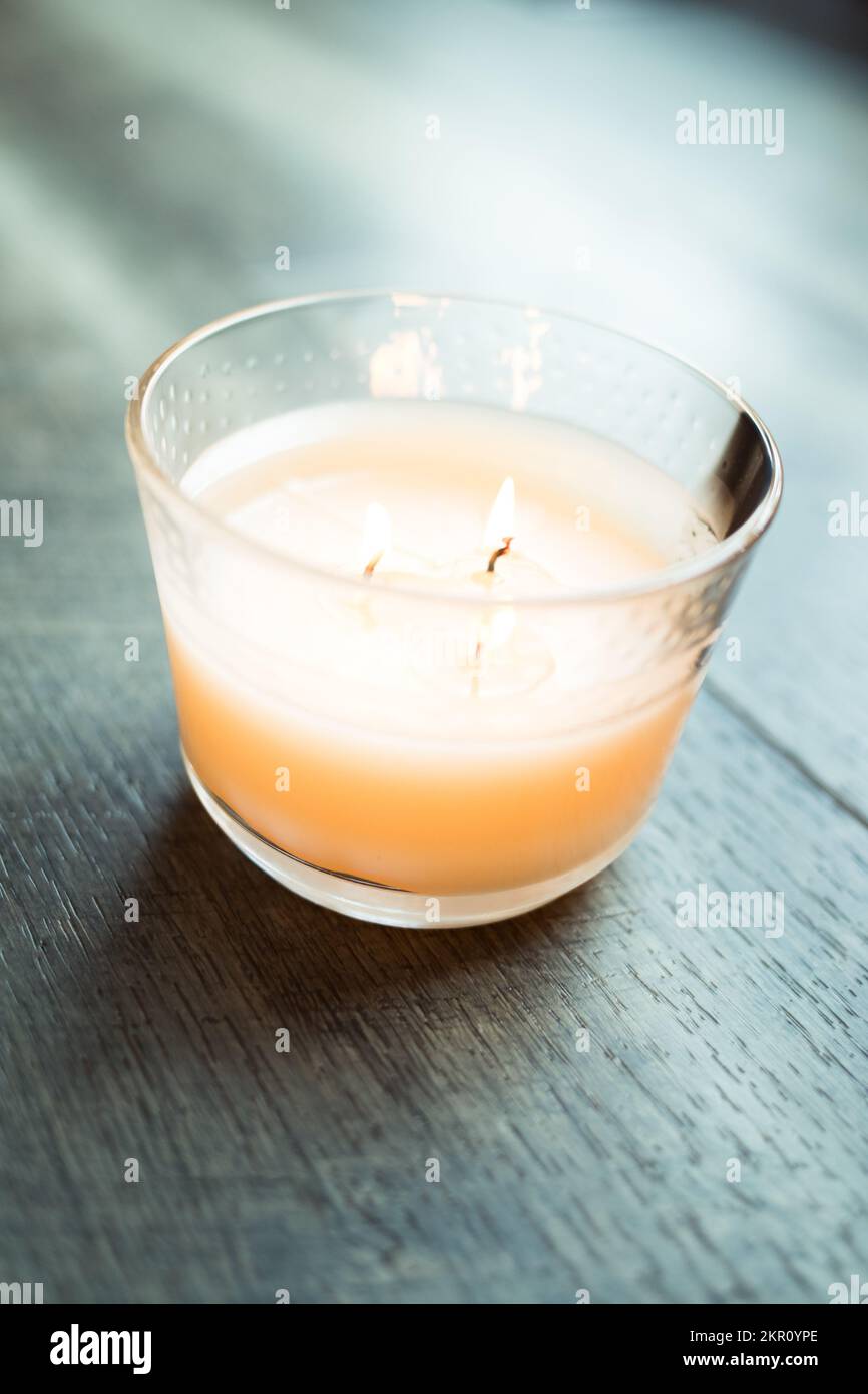 Cream colored burning candle on wood table Stock Photo - Alamy