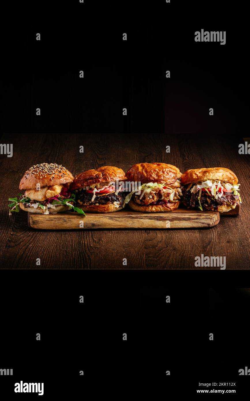 4 types of burgers on a wooden board Stock Photo - Alamy