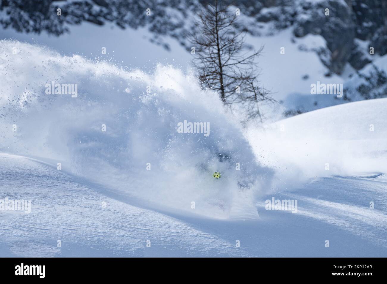 Ski pole sticking out of snow spray from a man skiing in deep powder ...
