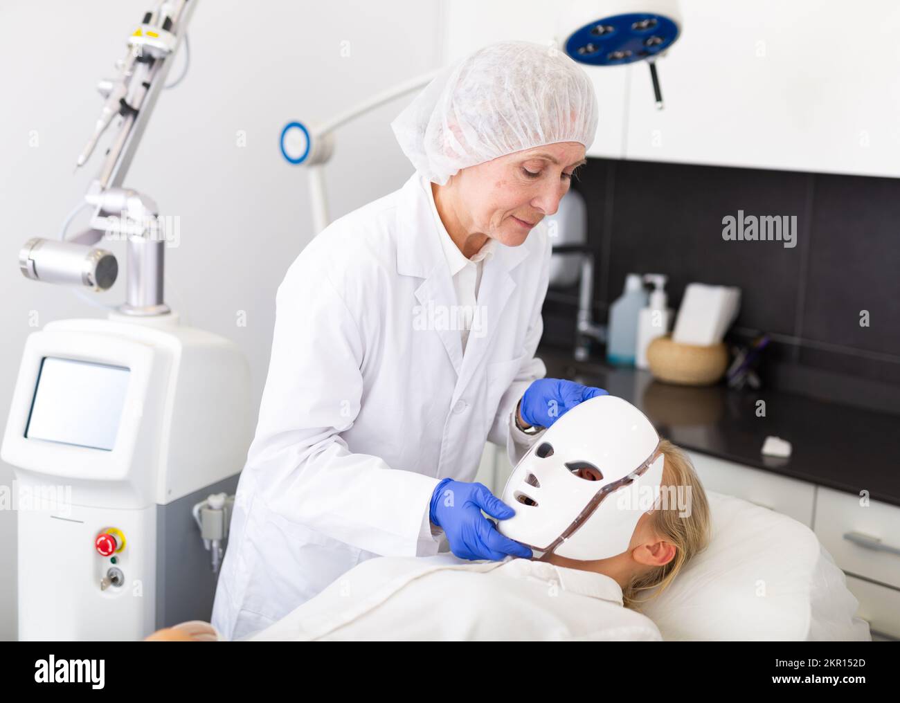 Young woman receiving facial light therapy in aesthetic medicine office ...