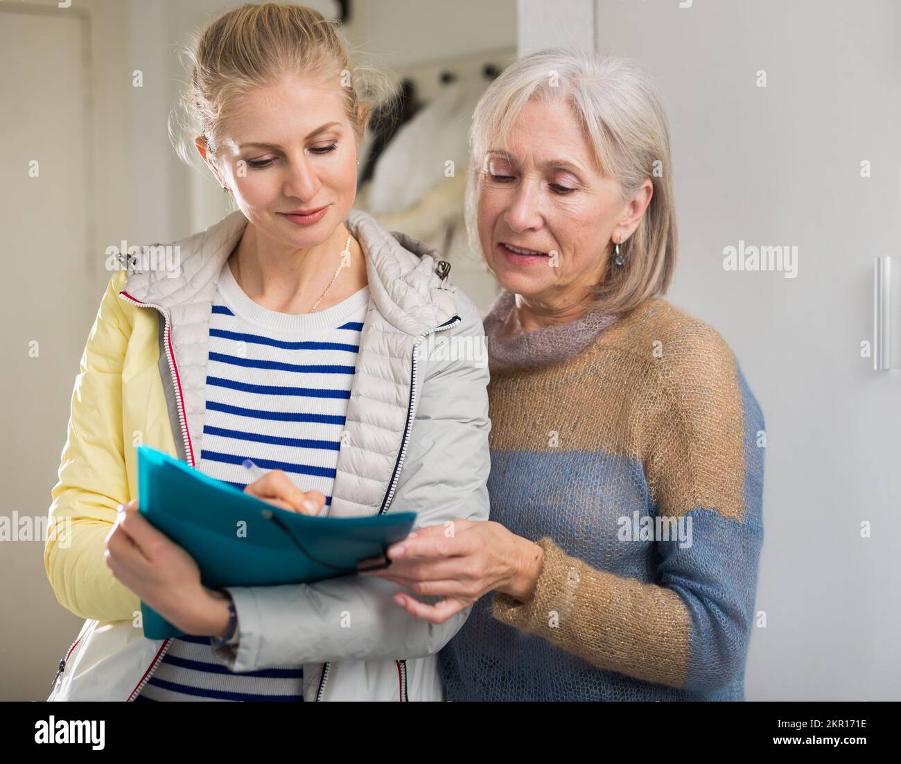 Young female social worker conducts a survey with an elderly woman ...