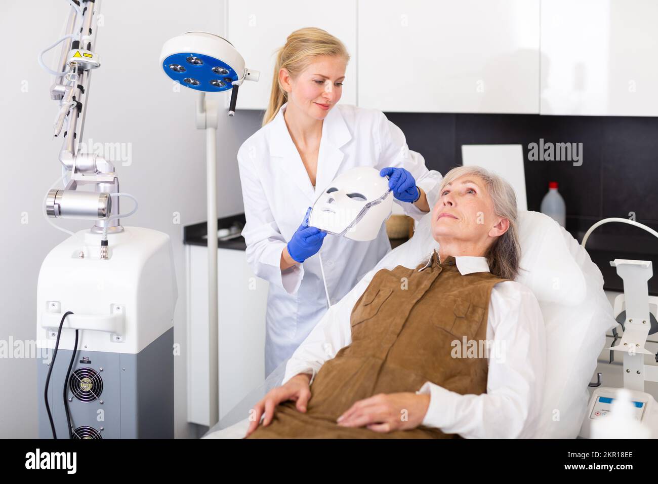 Elderly woman receiving facial light therapy in aesthetic medicine ...