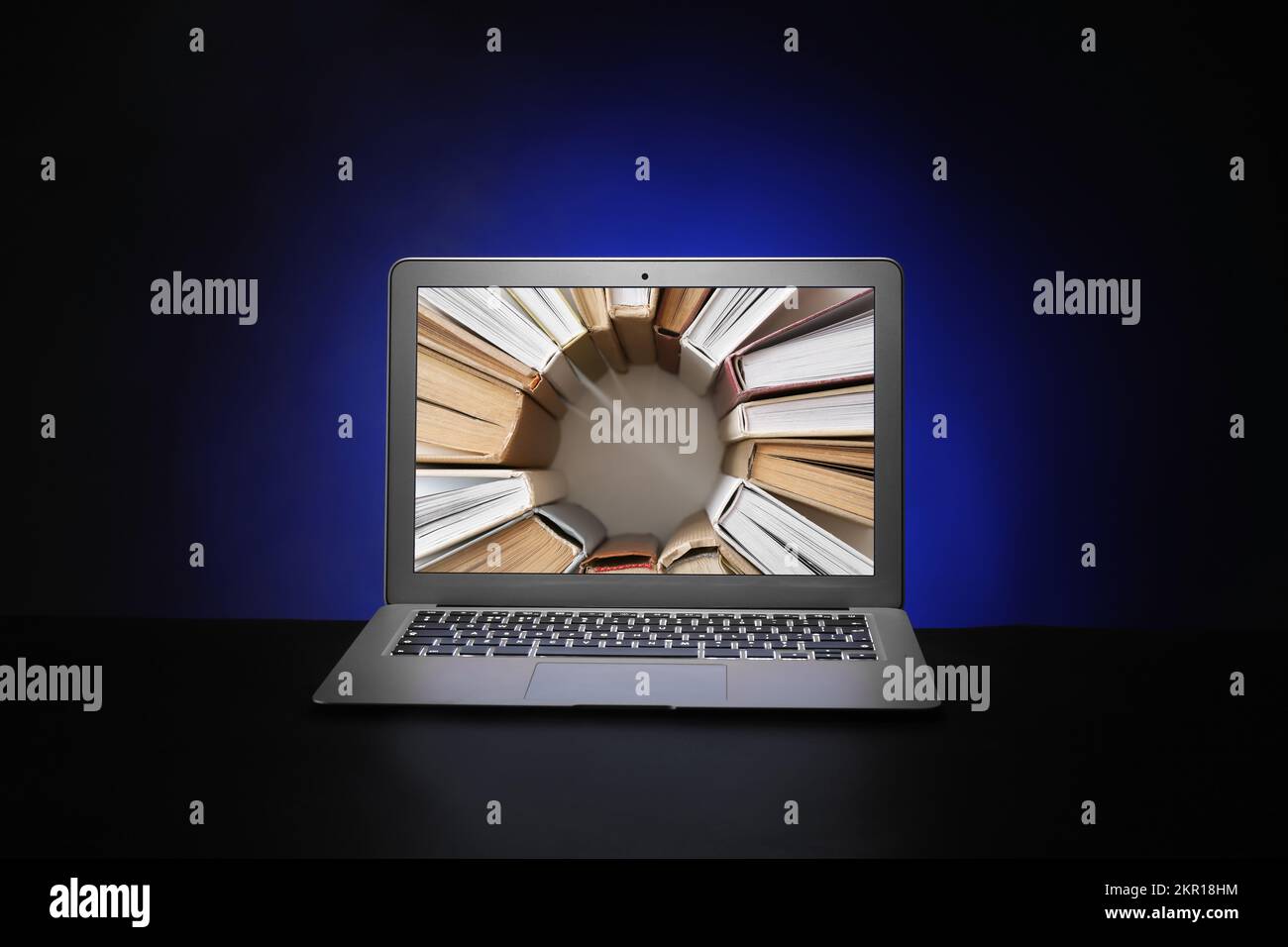 Many books on screen of modern laptop against dark background. Concept ...