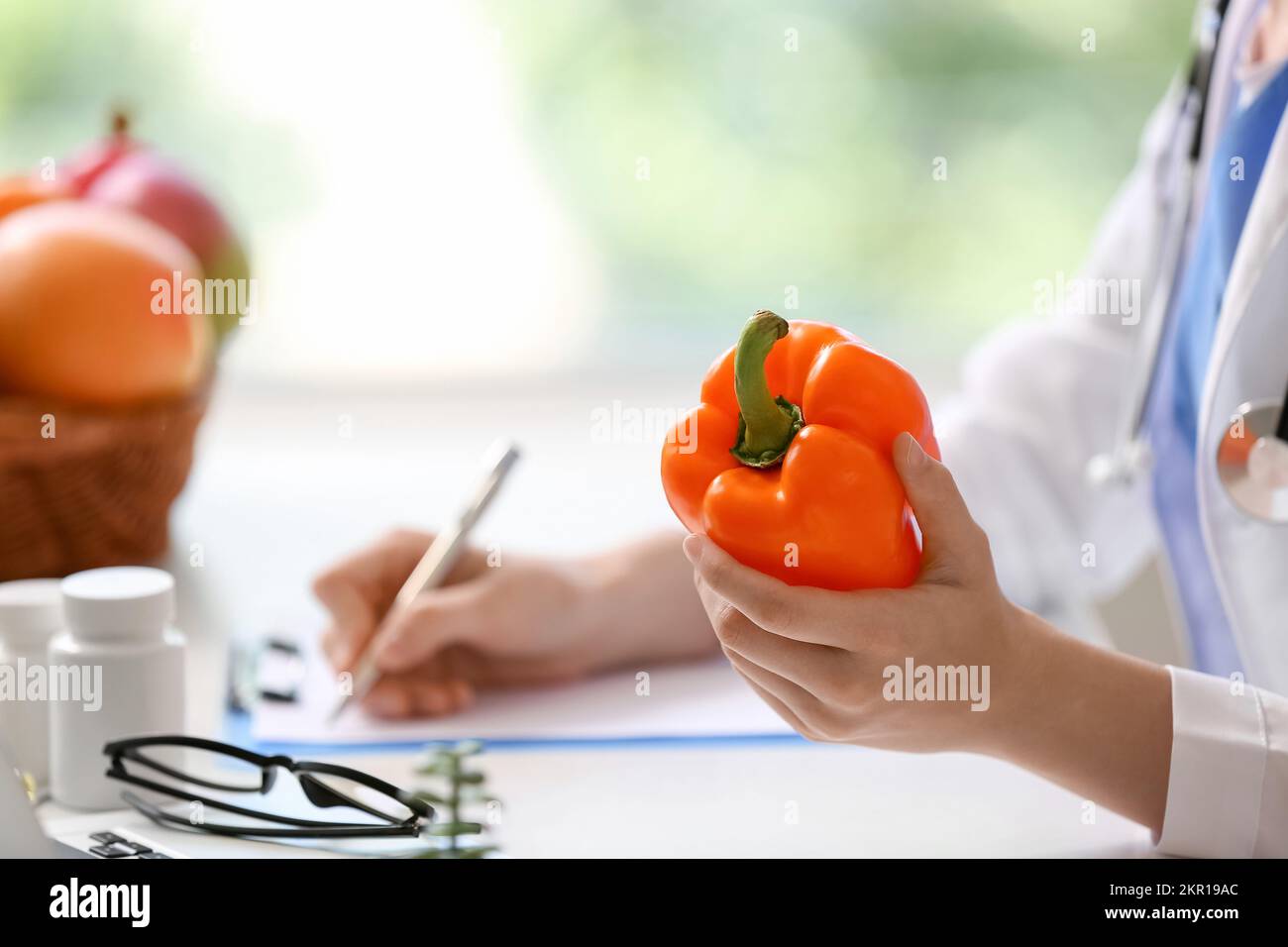 Female doctor with bell pepper writing in clipboard at hospital ...