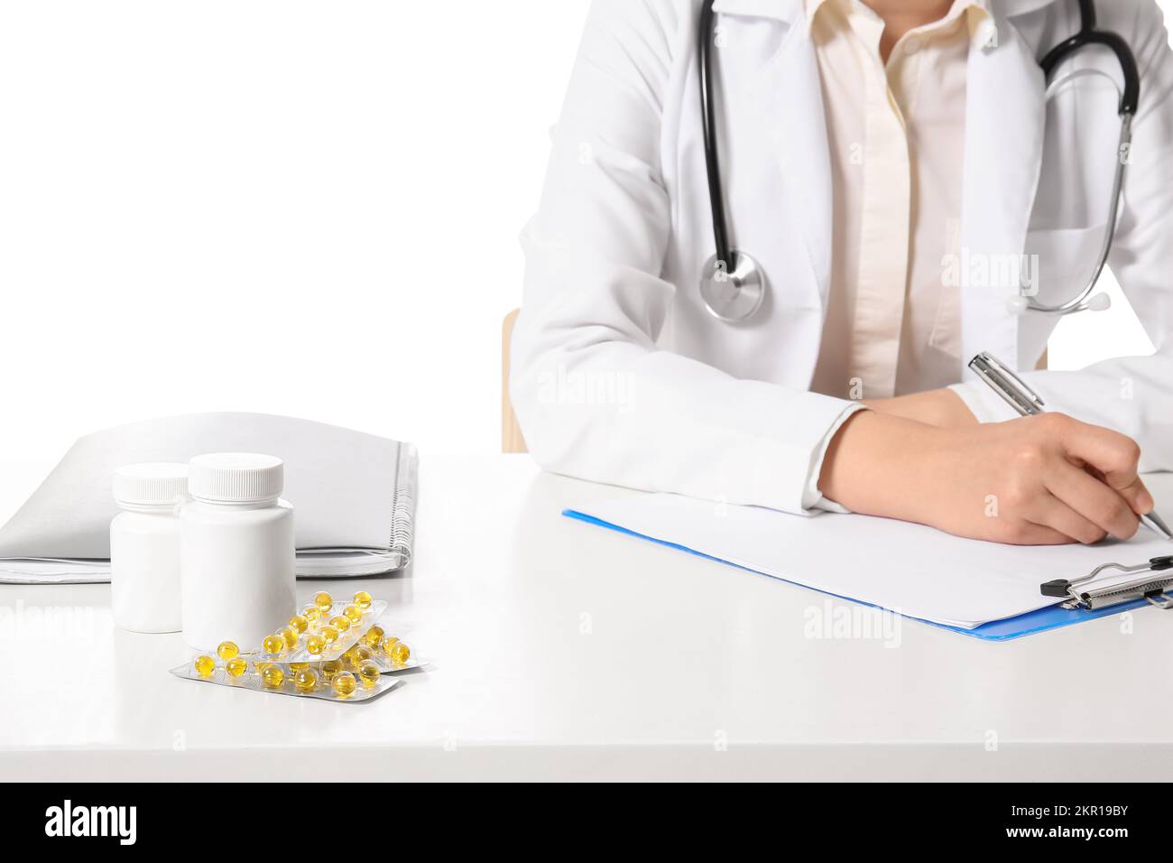 Female doctor writing in clipboard at table on white background Stock ...