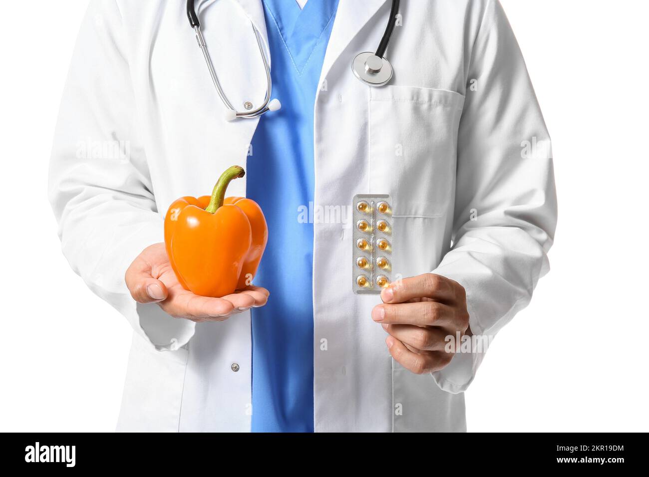 Male doctor with vitamins and bell pepper on white background, closeup ...