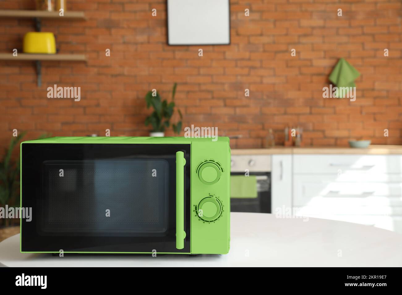 Modern green microwave oven on table in kitchen Stock Photo - Alamy