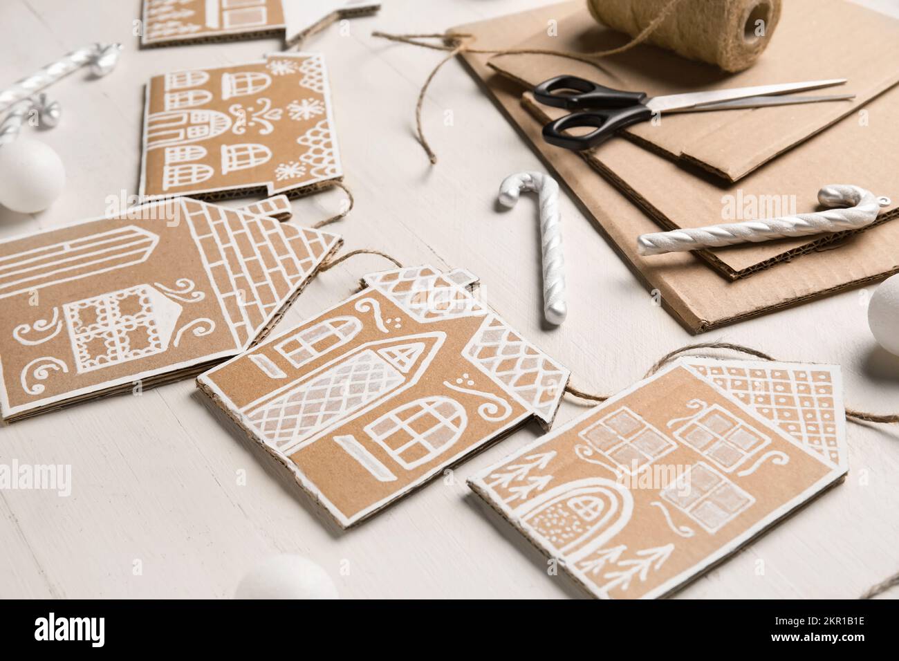 Cardboard houses with Christmas balls and candy canes on white wooden ...