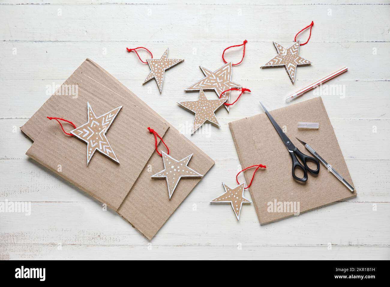 Christmas cardboard stars with scissors on white wooden background ...