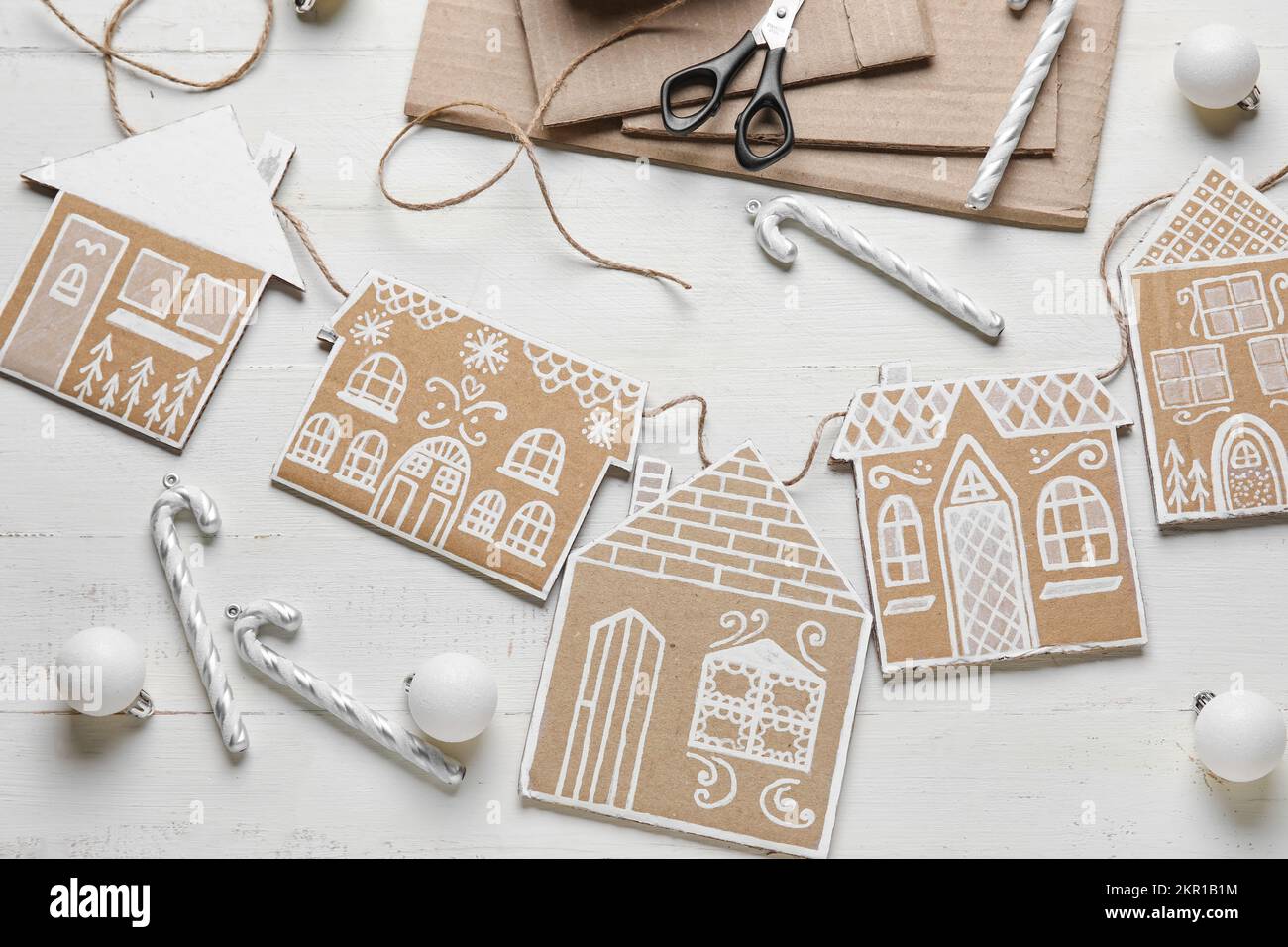 Cardboard houses with Christmas balls and candy canes on white wooden ...