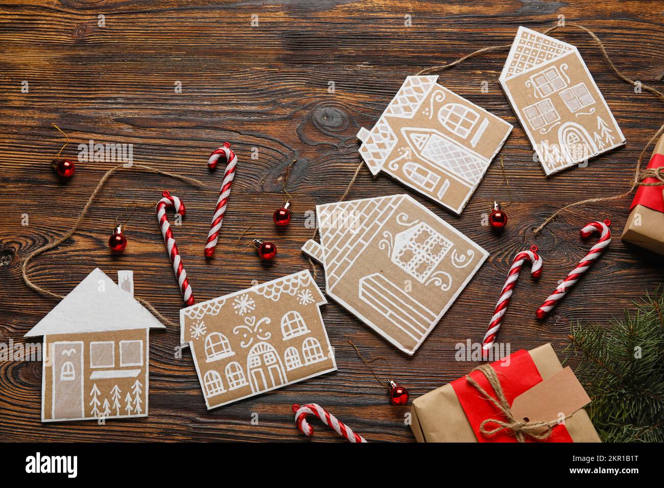 Cardboard houses with Christmas balls, candy canes and gifts on dark ...