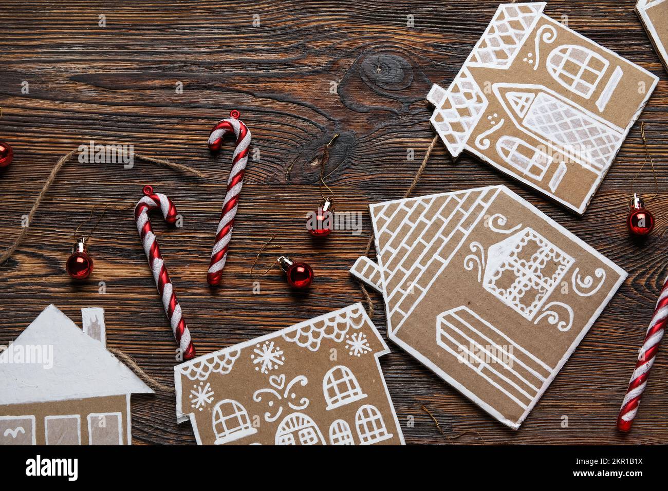 Cardboard houses with Christmas balls and candy canes on dark wooden ...
