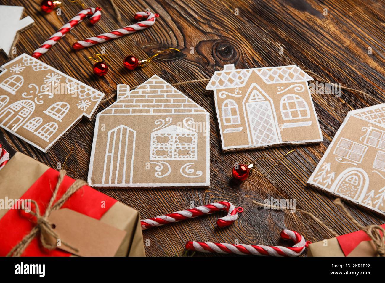 Cardboard houses with Christmas balls, candy canes and gifts on dark ...