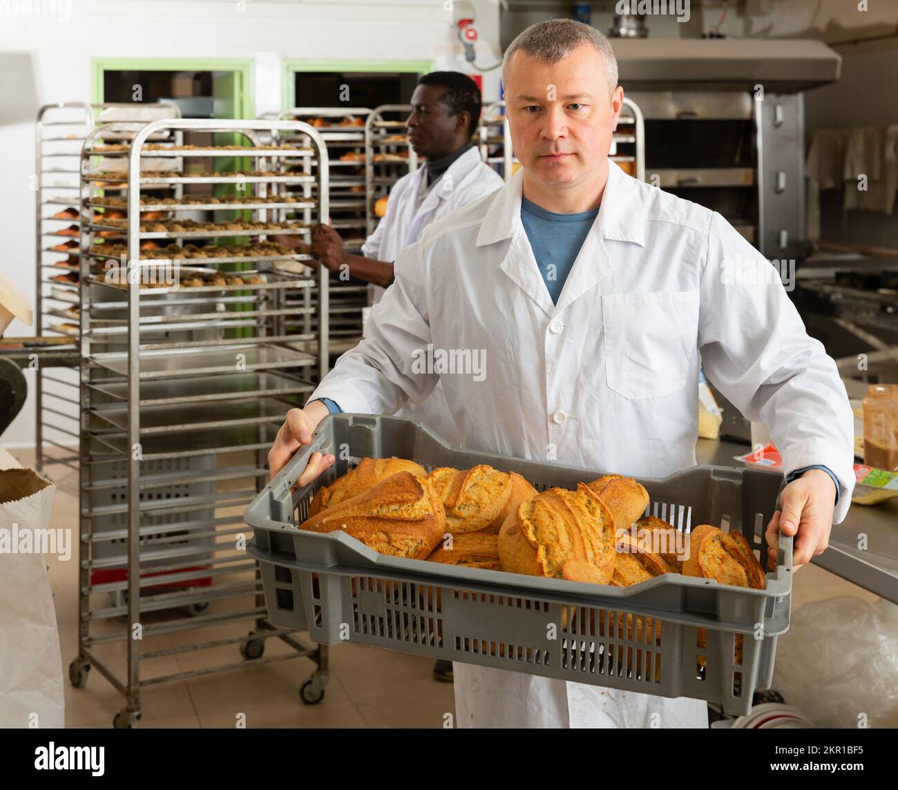Bakery worker carrying box with loaves Stock Photo - Alamy
