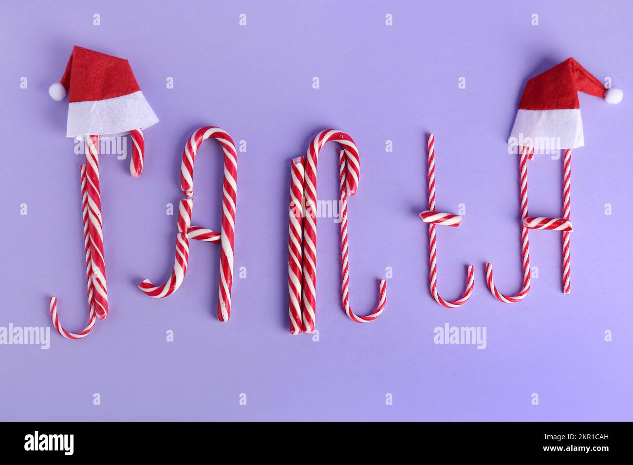 Word SANTA made of sweet candy canes and hats on color background Stock ...