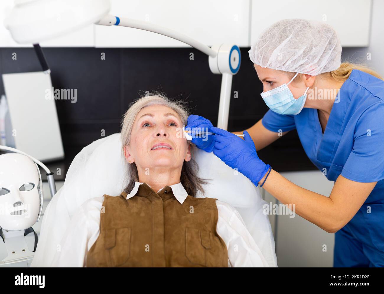 Professional beautician performing face contouring injections to aged ...
