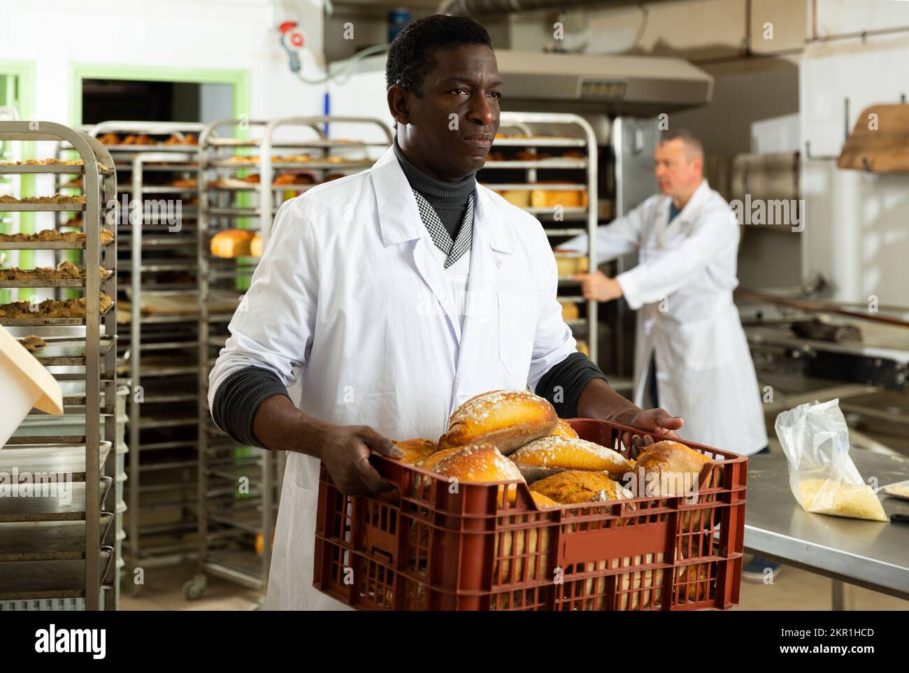 Baker with box with baguettes in bakery kitchen Stock Photo - Alamy