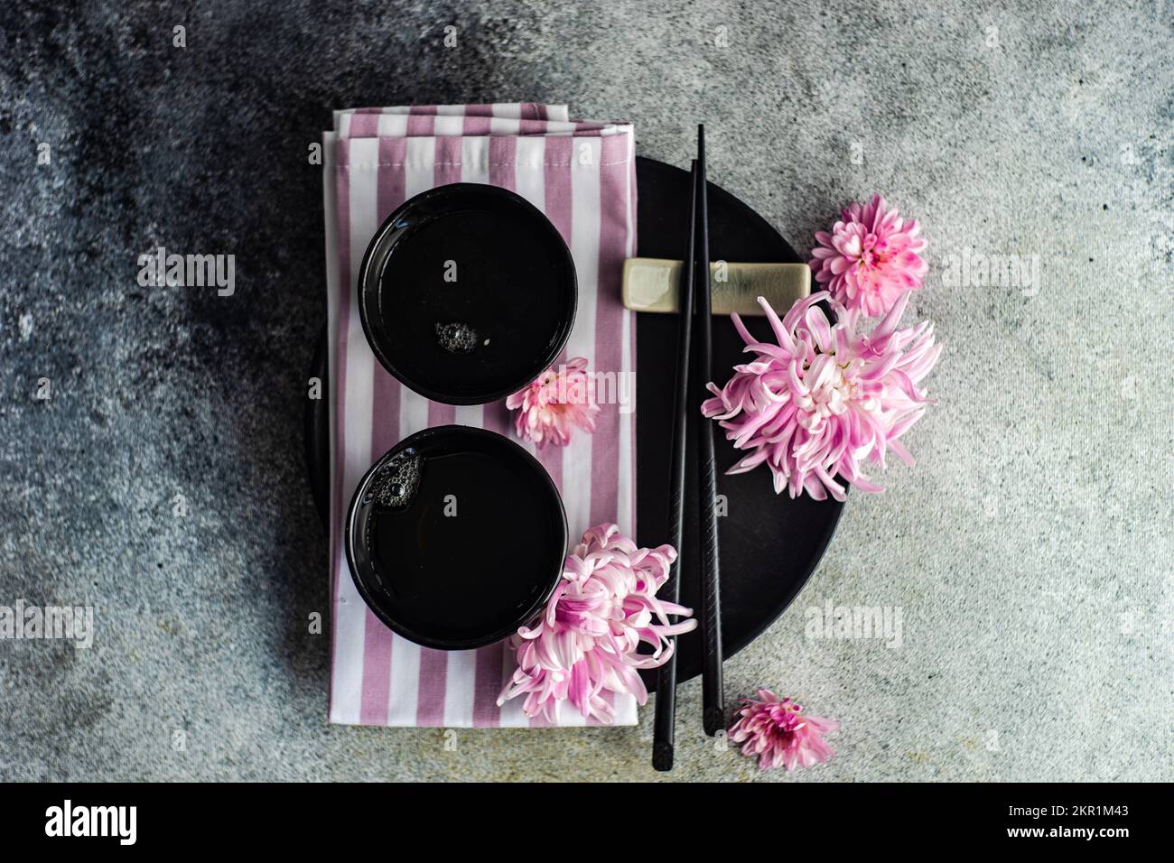 Overhead view of two cups of green tea on a plate with chopsticks and ...