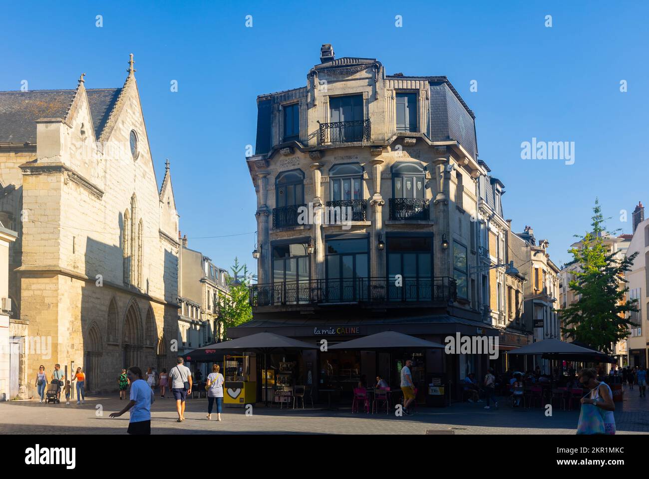 Reims street with open air cafes near facade of Church of Saint-Jacques ...