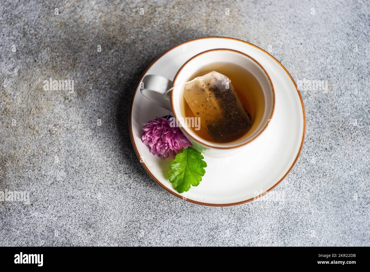 Overhead view of a cup of tea with teabag brewing and a purple ...