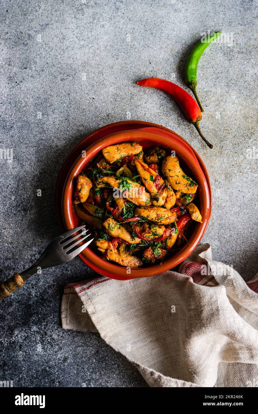 Overhead view of a bowl of fried chicken with roasted red peppers ...