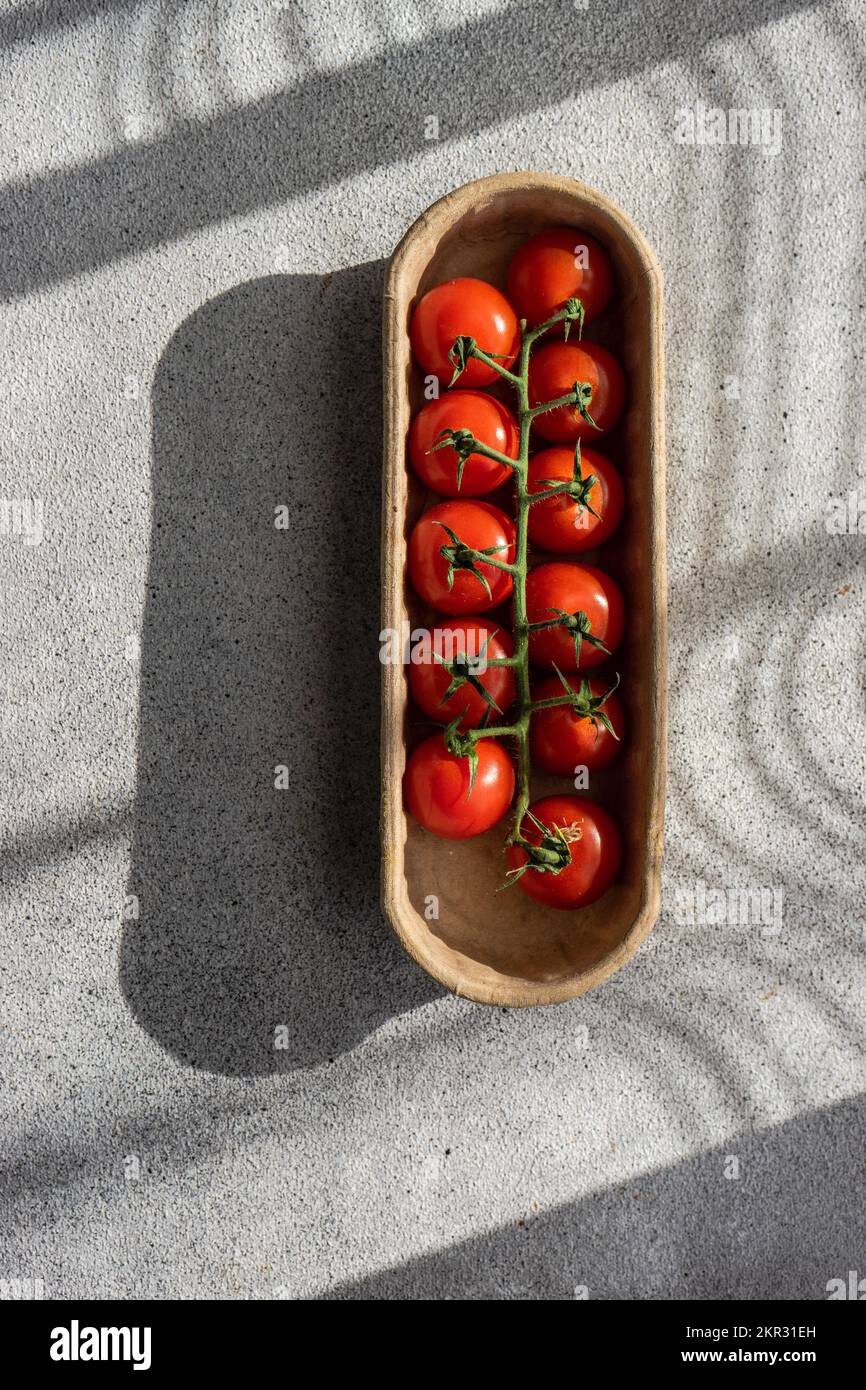 Overhead view of cherry vine tomatoes in a cardboard carton in sunlight ...