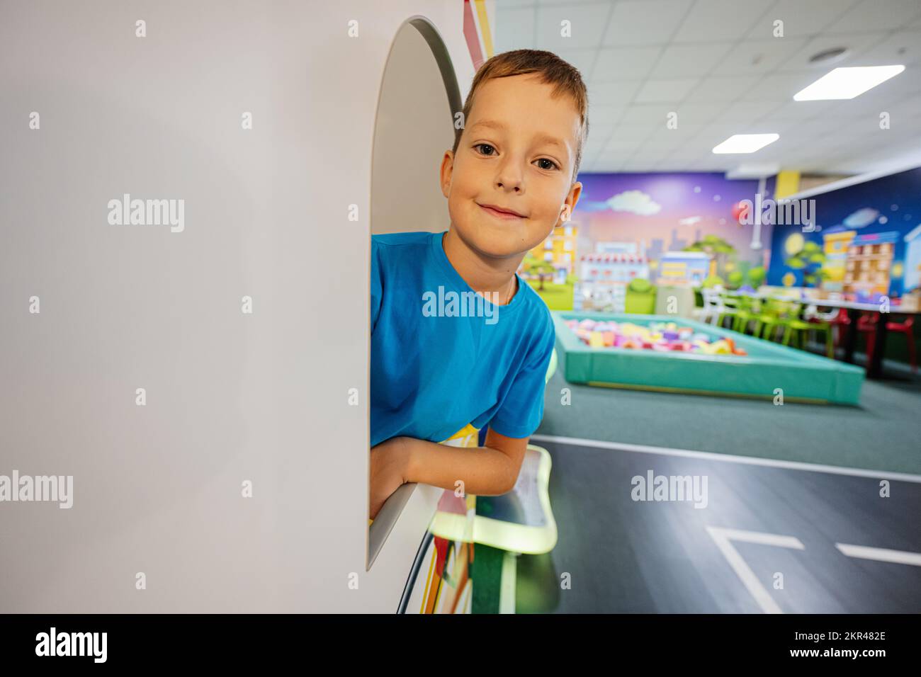 Boy playing at indoor play center playground, looking from window Stock ...