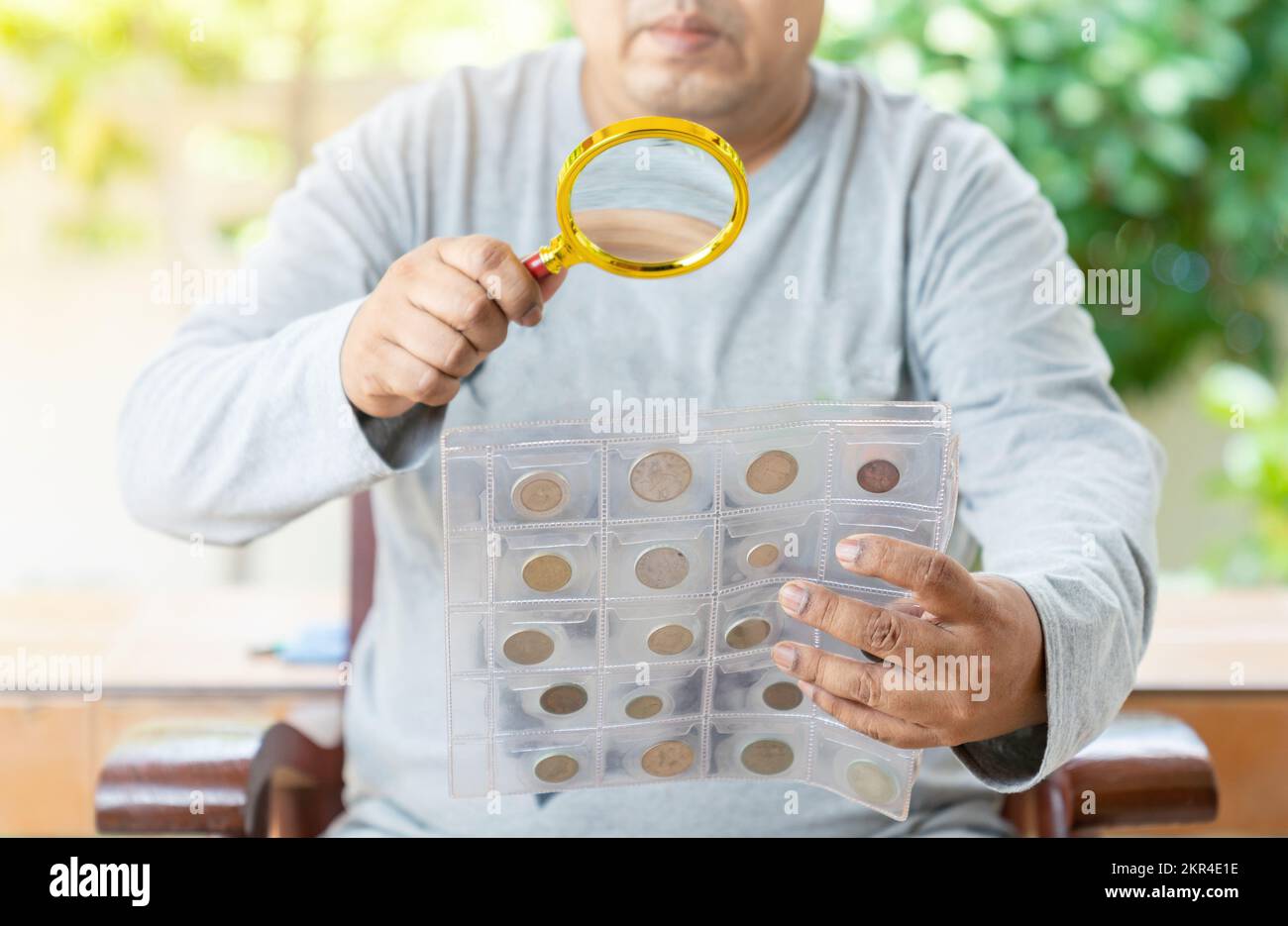 Views coins from a coin album through a magnifying glass on out of ...