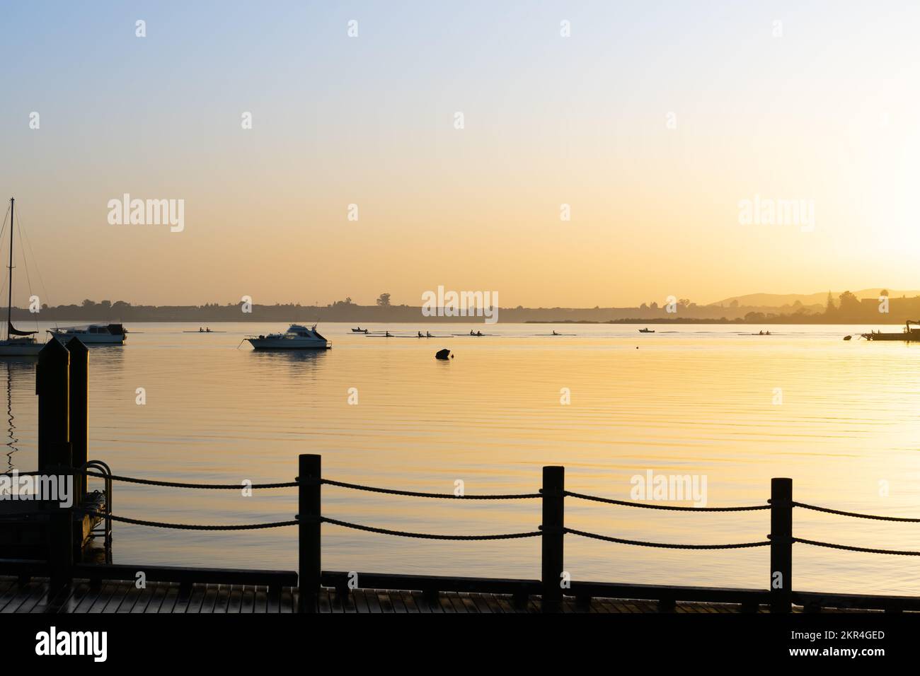 Golden hues of Tauranga Downtown waterfront sunrise over calm harbour ...