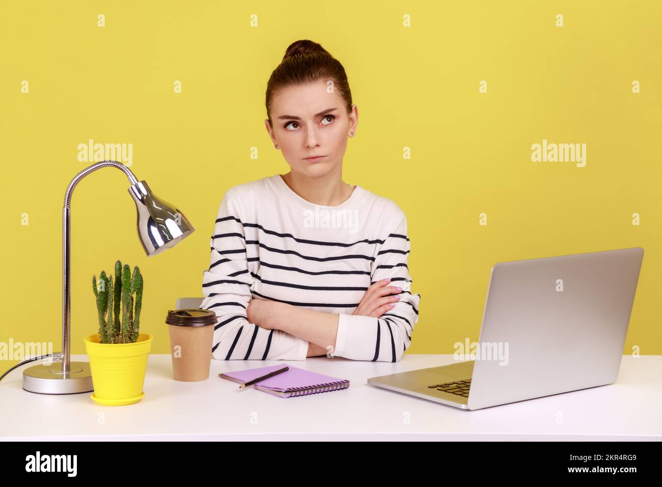 Pensive puzzled woman in striped shirt sitting with thoughtful confused ...