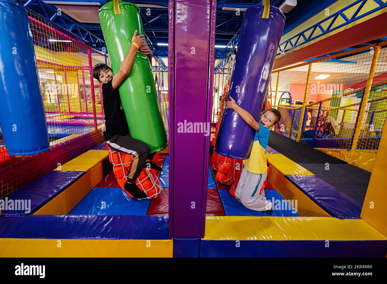 Playing at indoor play center playground, brothers in punching bags ...