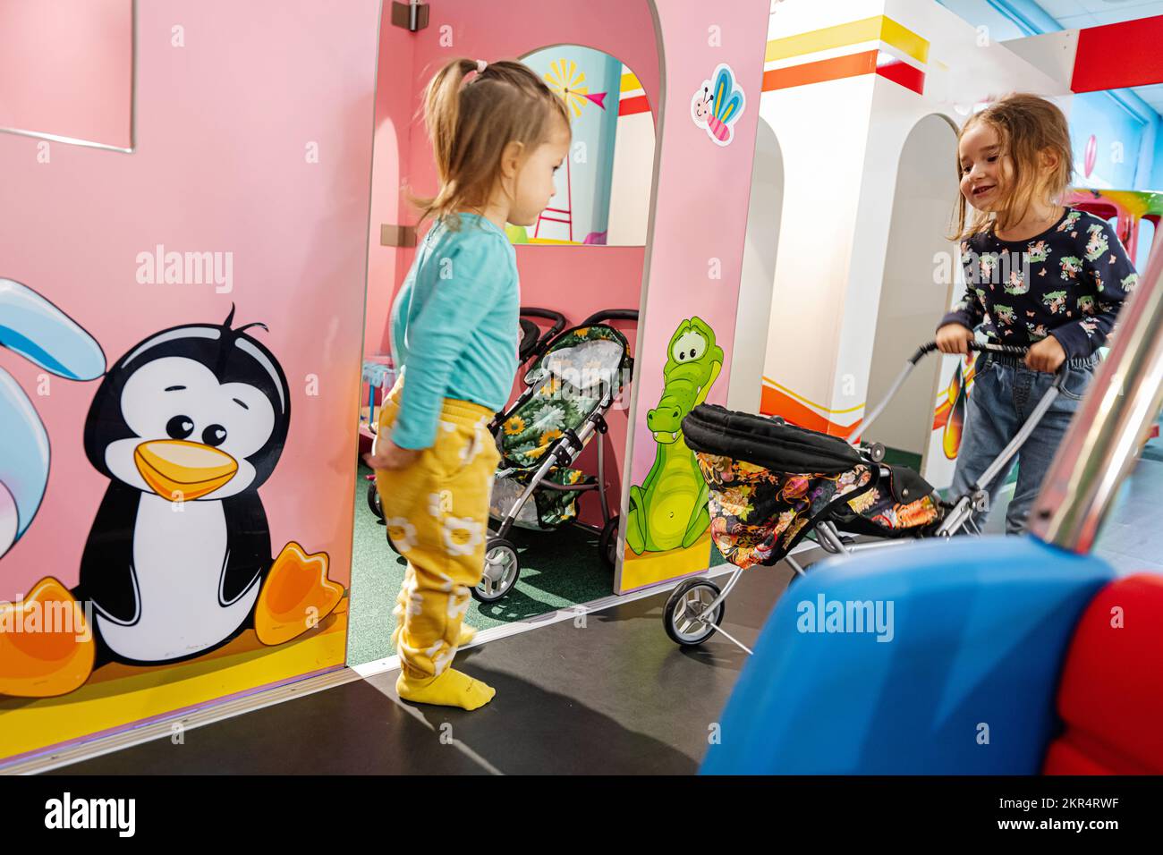 Sisters playing with baby carriage at indoor play center playground ...