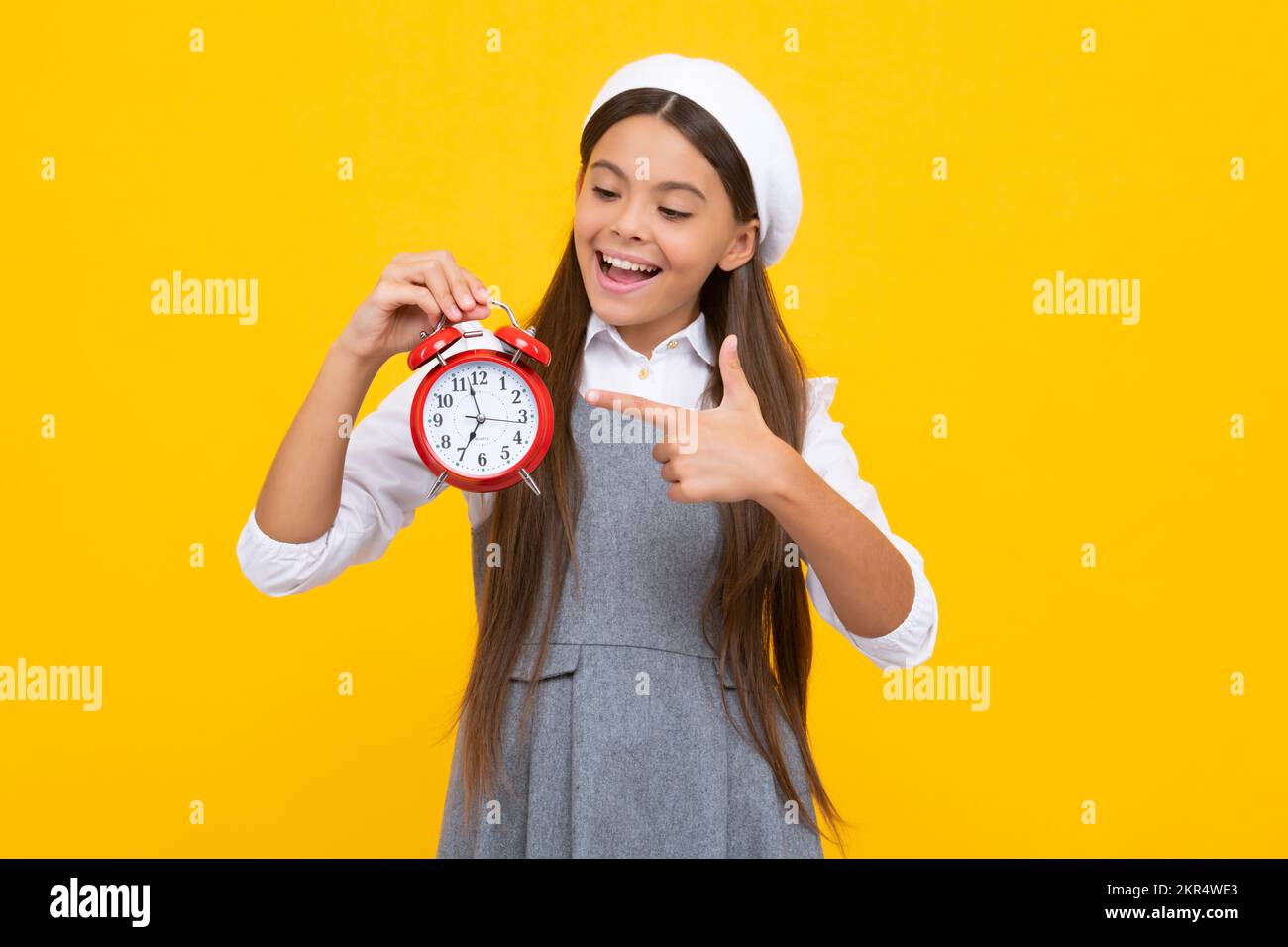 Teen student girl hold clock isolated on yellow background. Time to ...