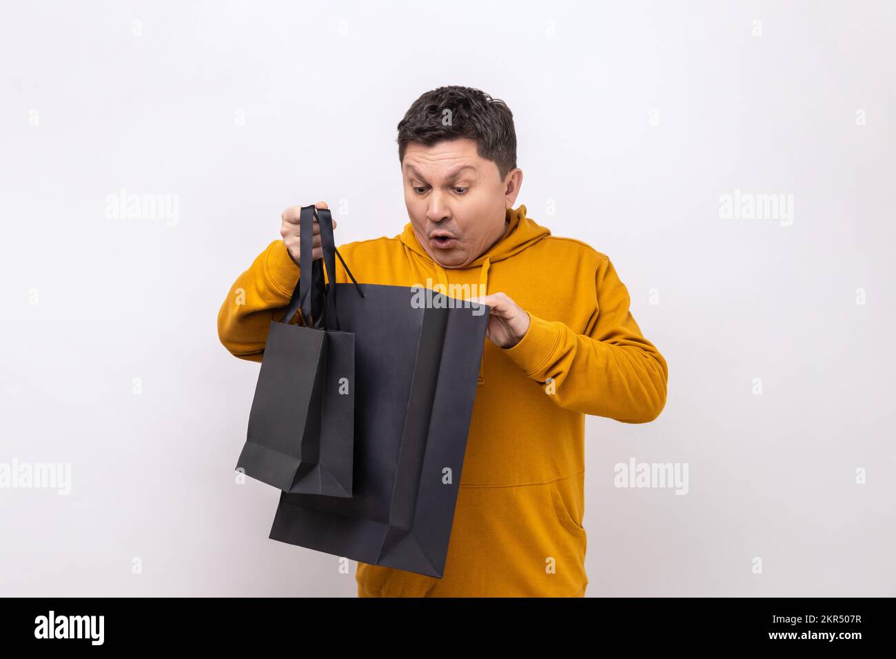 Portrait of middle aged man standing holding black shopping bags and ...
