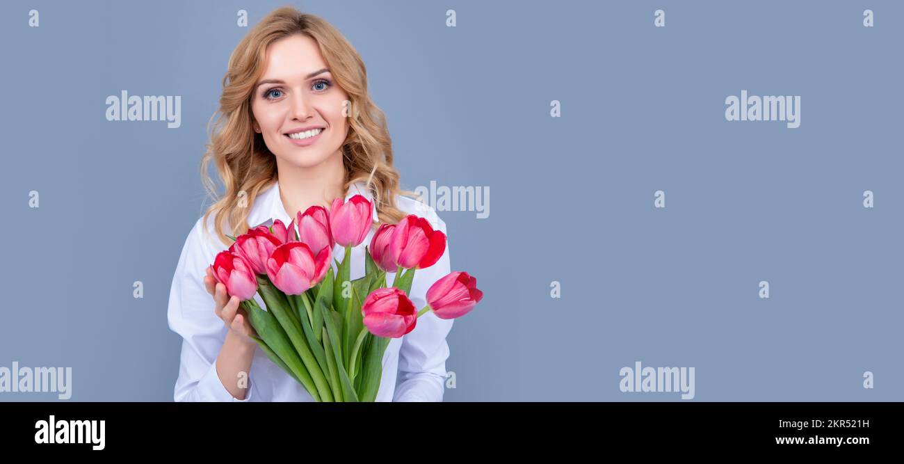 smiling young woman with spring tulip bouquet on grey background. Woman ...